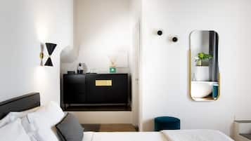 Quarto moderno com cama, cômoda preta, espelho e um banquinho azul.