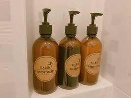 Três frascos de sabonete líquido, shampoo e condicionador Karin em uma prateleira.