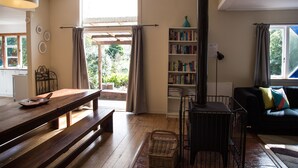 Uma sala de estar acolhedora com um banco de madeira, uma estante e um sofá preto com almofadas coloridas.