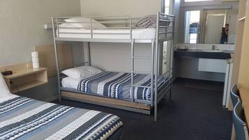 Quarto com beliche, escrivaninha, espelho e banheiro.
