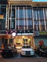 Um hotel com fachada moderna, entrada visível e vários carros estacionados em frente.