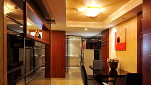 Um hall de hotel moderno com divisória de vidro, área de refeições com mesa e cadeiras, e um vaso decorativo na parede.
