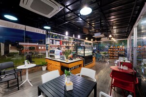 Interior de uma cafeteria com balcão, área de estar e vista para o exterior.