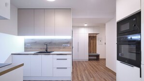 Uma cozinha moderna com armários brancos, bancada de madeira e eletrodomésticos embutidos.
