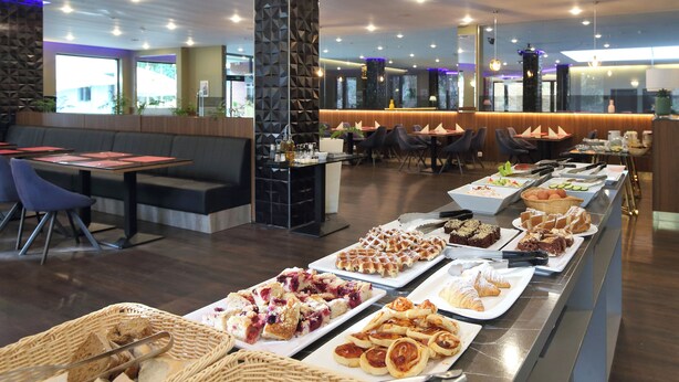 Buffet com diversos alimentos, disposição de mesas e decoração moderna.