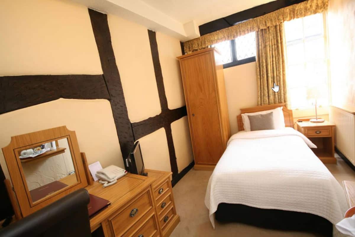 Quarto com uma cama grande, um guarda-roupa, uma escrivaninha com espelho e uma mesa de cabeceira.