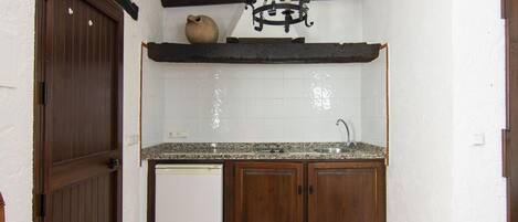 Uma cozinha compacta com lava-louças embutida, armários de madeira, bancada de granito e luminária pendente.
