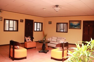 Um quarto com um sofá, duas cadeiras, uma mesa e um quadro na parede.