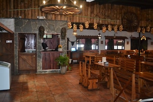 Interior rústico de restaurante com paredes de pedra, bancos de madeira e cebolas penduradas.