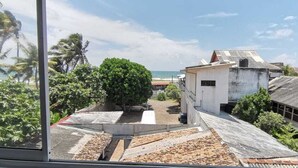 Vista da janela com vista para um pátio, um edifício, árvores e céu claro.