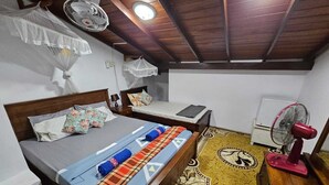 Quarto com cama, mesas de cabeceira, ventoinha, aquecedor e tapete estampado.