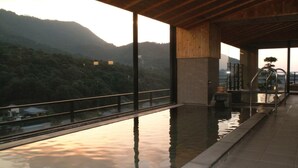 Piscina interior moderna com vista para um morro arborizado.