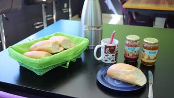 Uma mesa com uma cesta de pão, uma caneca de café e dois potes de geleia.