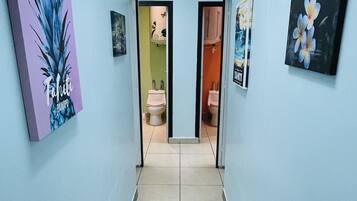 Um corredor com paredes azul claro, chão ladrilhado e obras de arte nas paredes.
