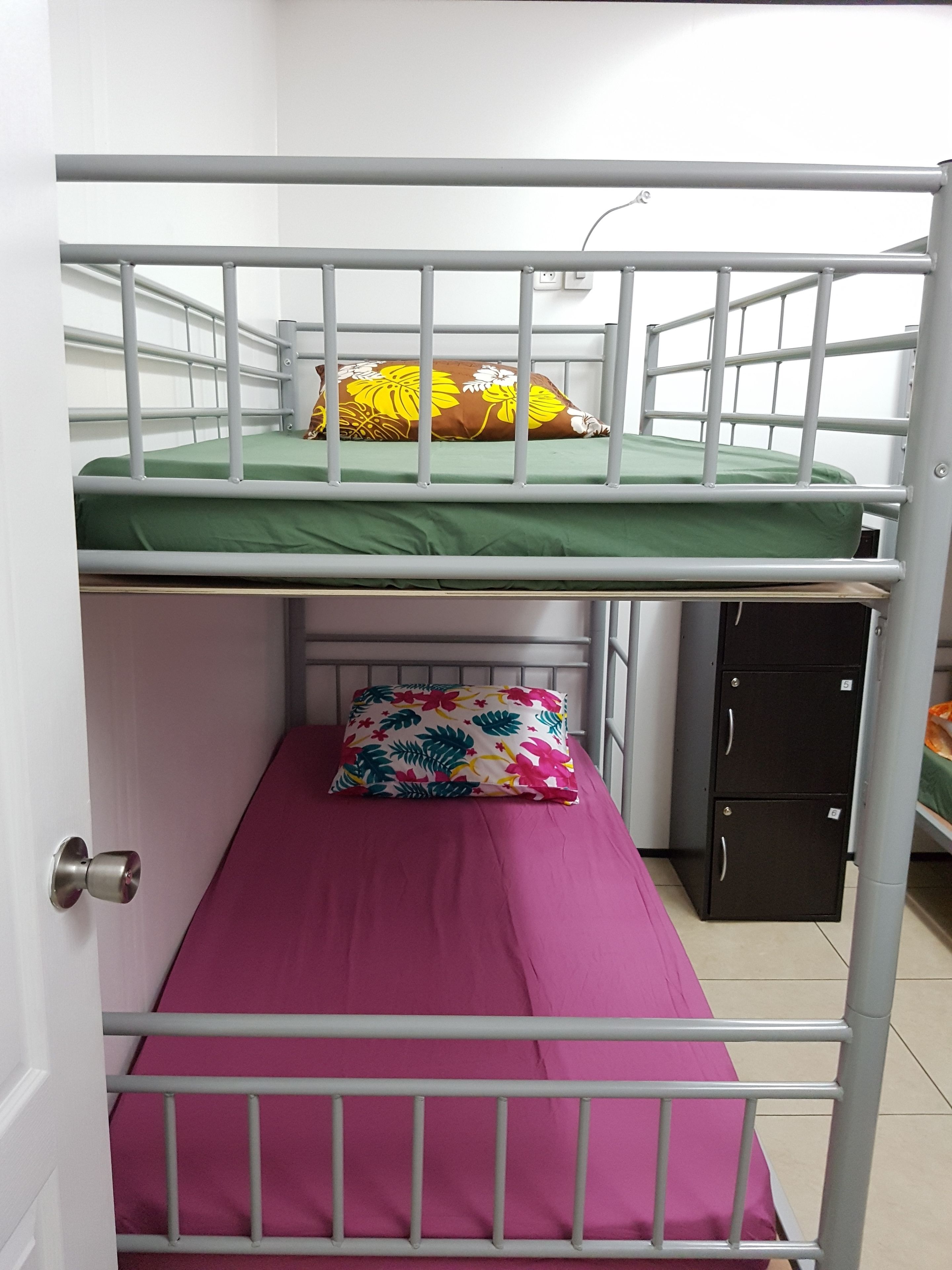 Uma cama beliche com colchão verde e almofada florida na cama de baixo.