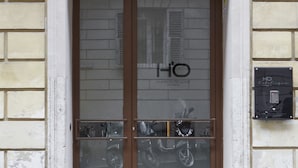 Uma porta dupla com um painel de vidro, uma motocicleta estacionada na frente e uma caixa de correio na parede.