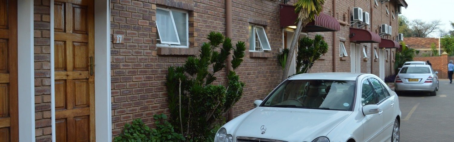 Um carro branco estacionado em frente a um prédio de tijolos com o número 17 na porta.