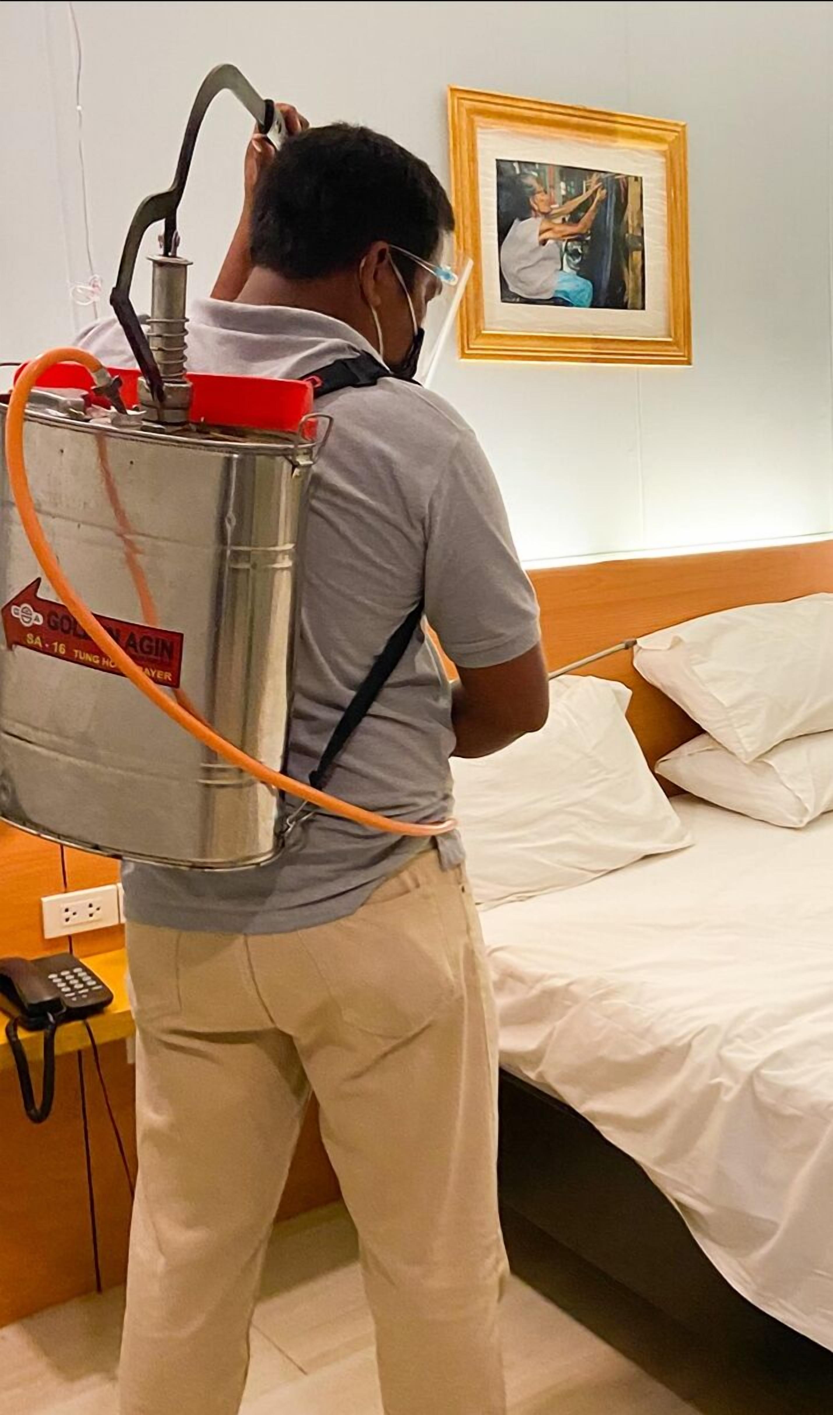 Uma pessoa num quarto de hotel com um aparelho purificador de ar portátil preso às costas.