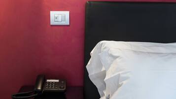 Quarto de hotel com cama, telefone e tomada na parede.