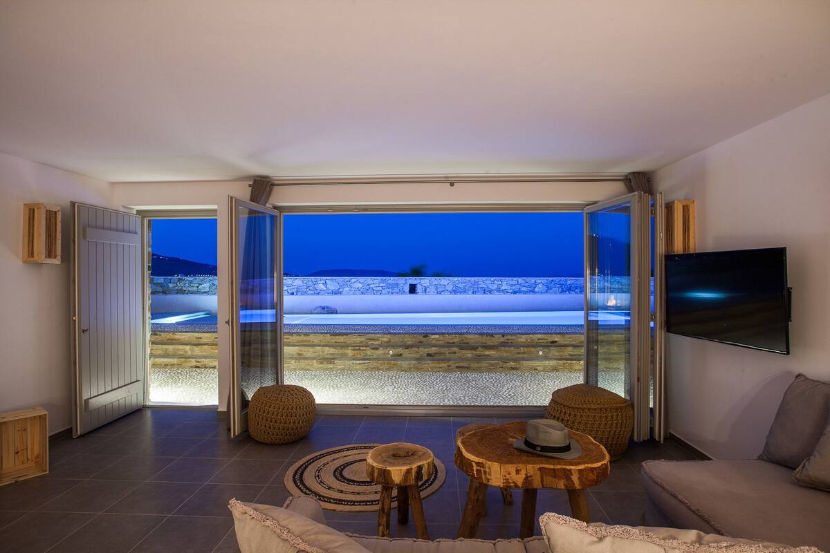 Uma sala de estar moderna com uma grande porta de vidro que dá para uma vista externa deslumbrante.