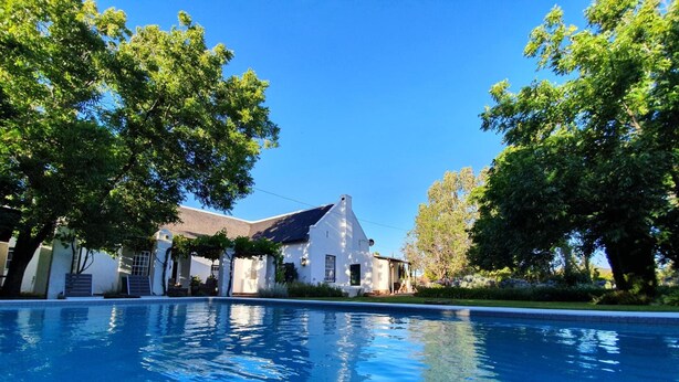 Piscina com uma casa ao fundo.