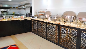 Disposição de buffet com diversos alimentos e um painel decorativo.