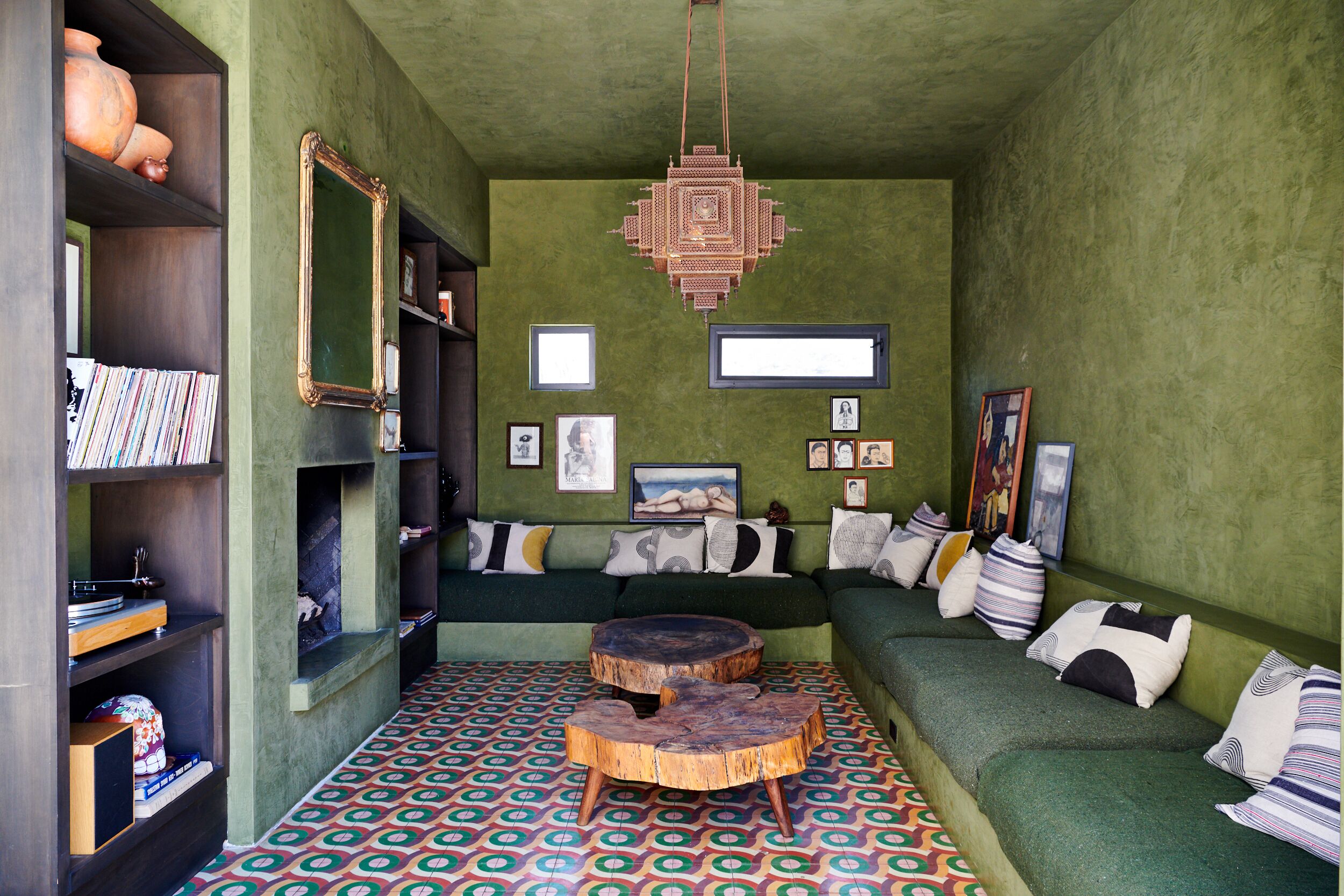 Uma sala de estar acolhedora com um sofá verde, uma mesa de centro de madeira e um chão estampado.