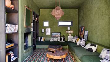 Uma sala de estar acolhedora com um sofá verde, uma mesa de centro de madeira e um chão estampado.