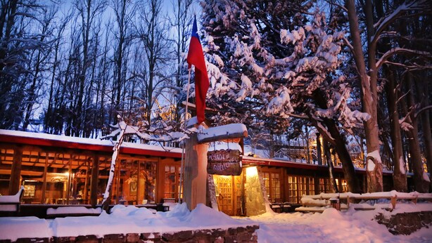 Um edifício coberto de neve com uma placa que indica um restaurante.