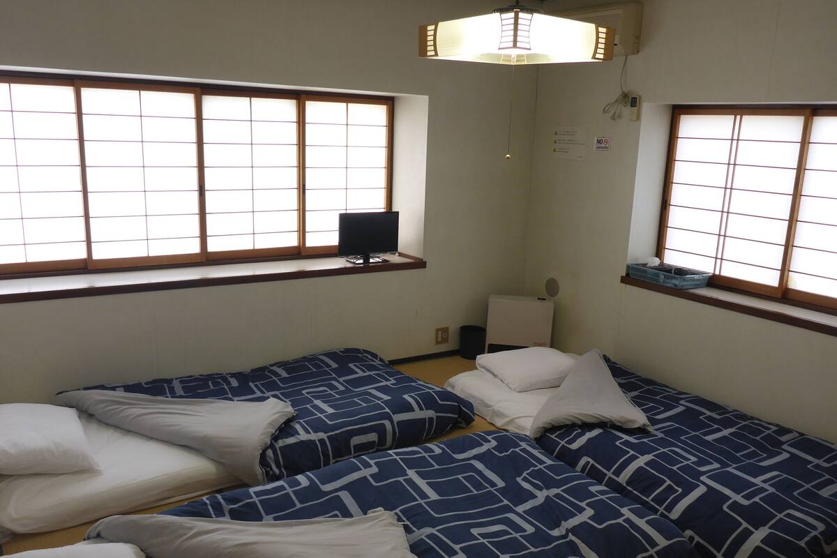 Quarto com duas camas, uma televisão em uma estante e uma janela com vista.