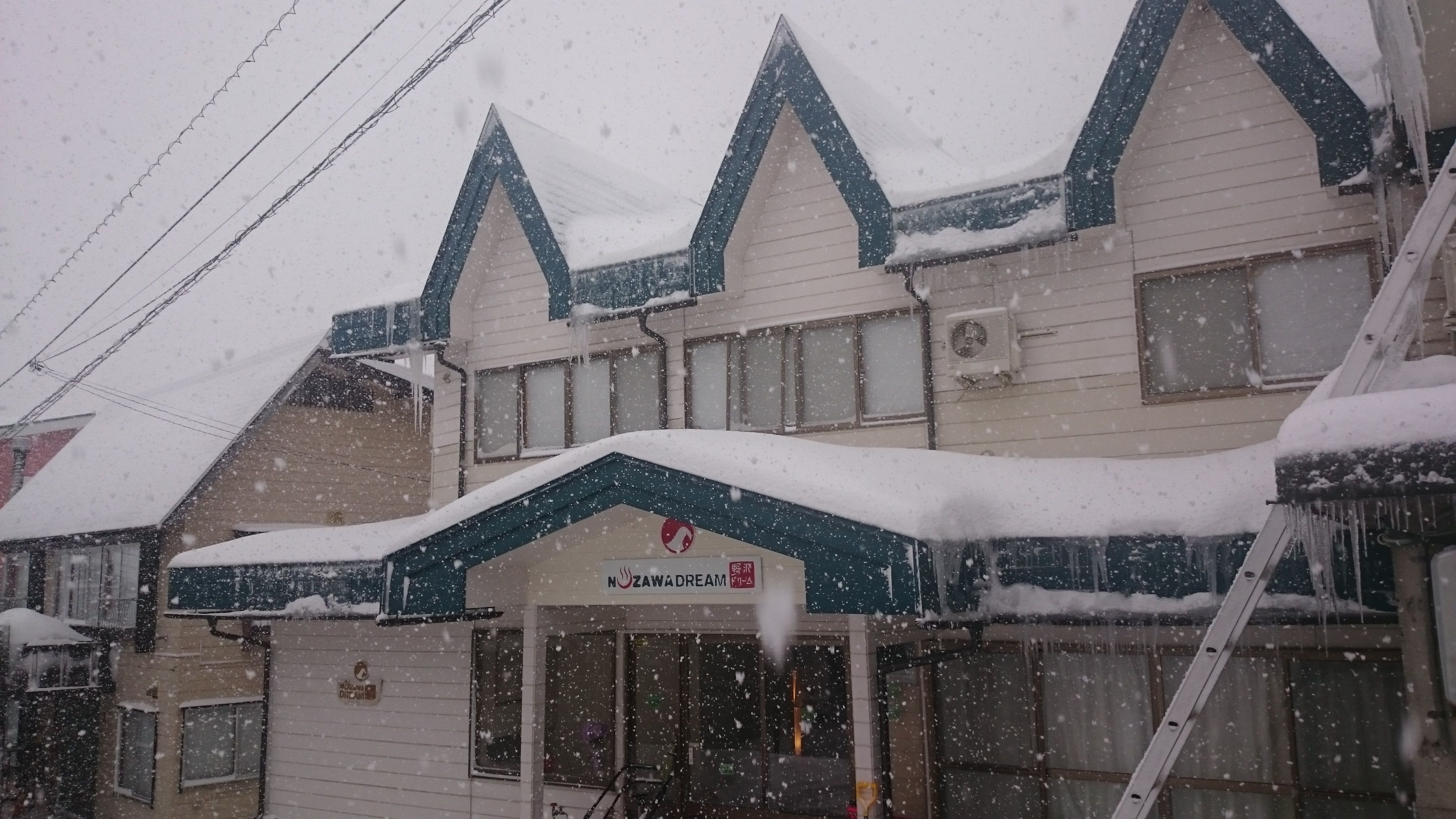 Um edifício com o telhado coberto de neve e uma placa com a inscrição 'ZAWADREAM'.