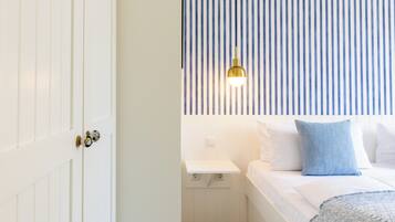 Quarto com cama, mesa de cabeceira e luminária pendente.