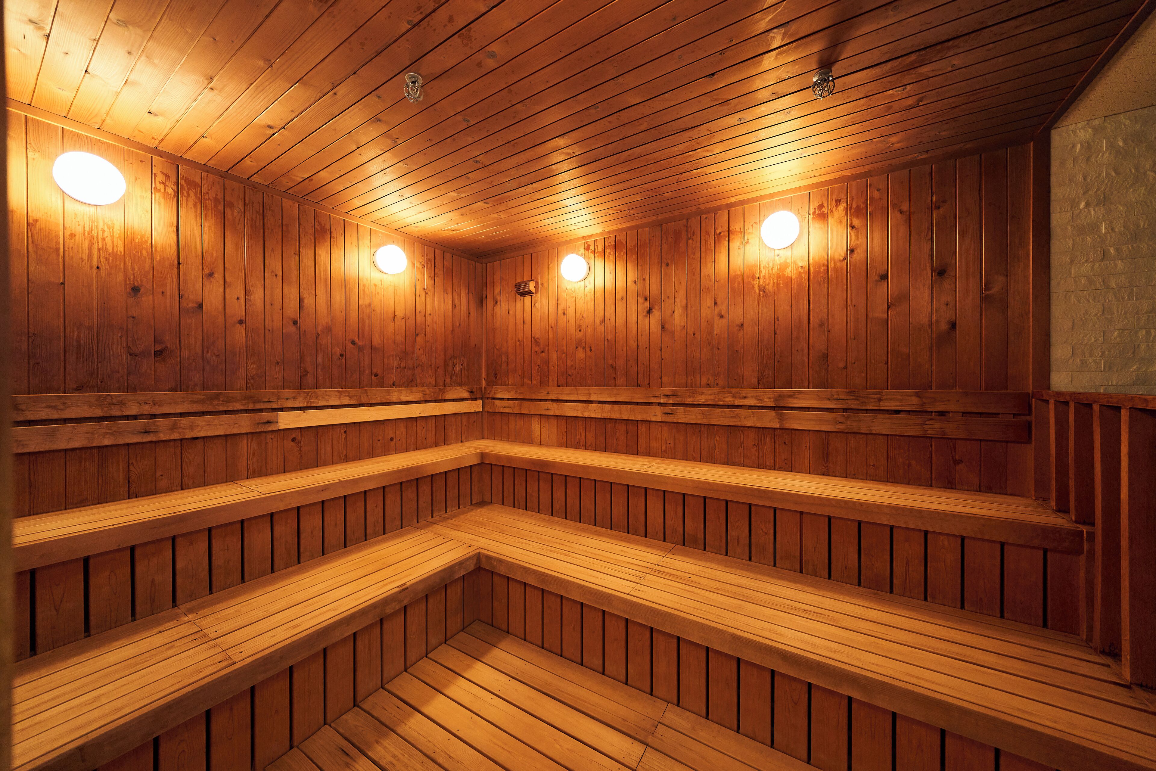 Uma sauna com bancos de madeira e três luzes no teto.