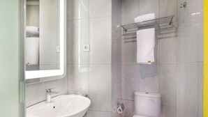 Casa de banho moderna com lavatório, espelho, sanita e porta-toalhas.