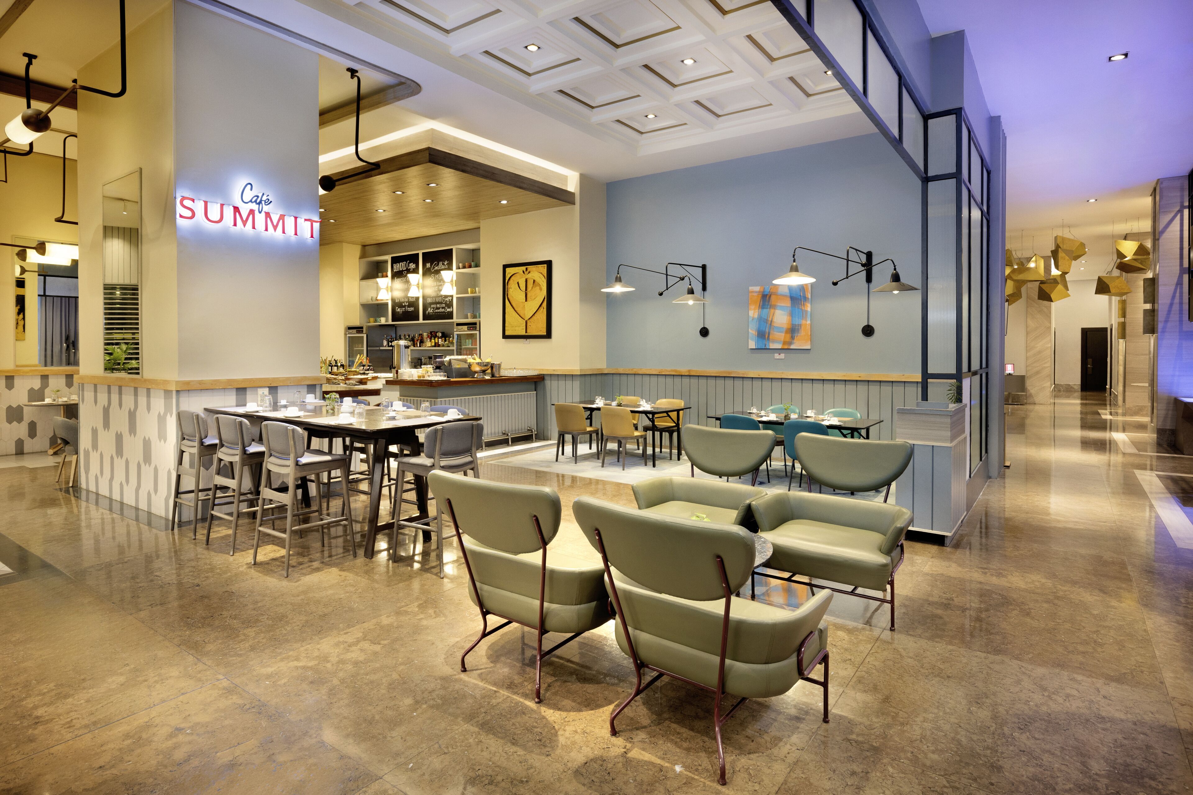 Um saguão de hotel moderno com área de bar, assentos e um letreiro chamativo que diz 'Cafe Summit'.