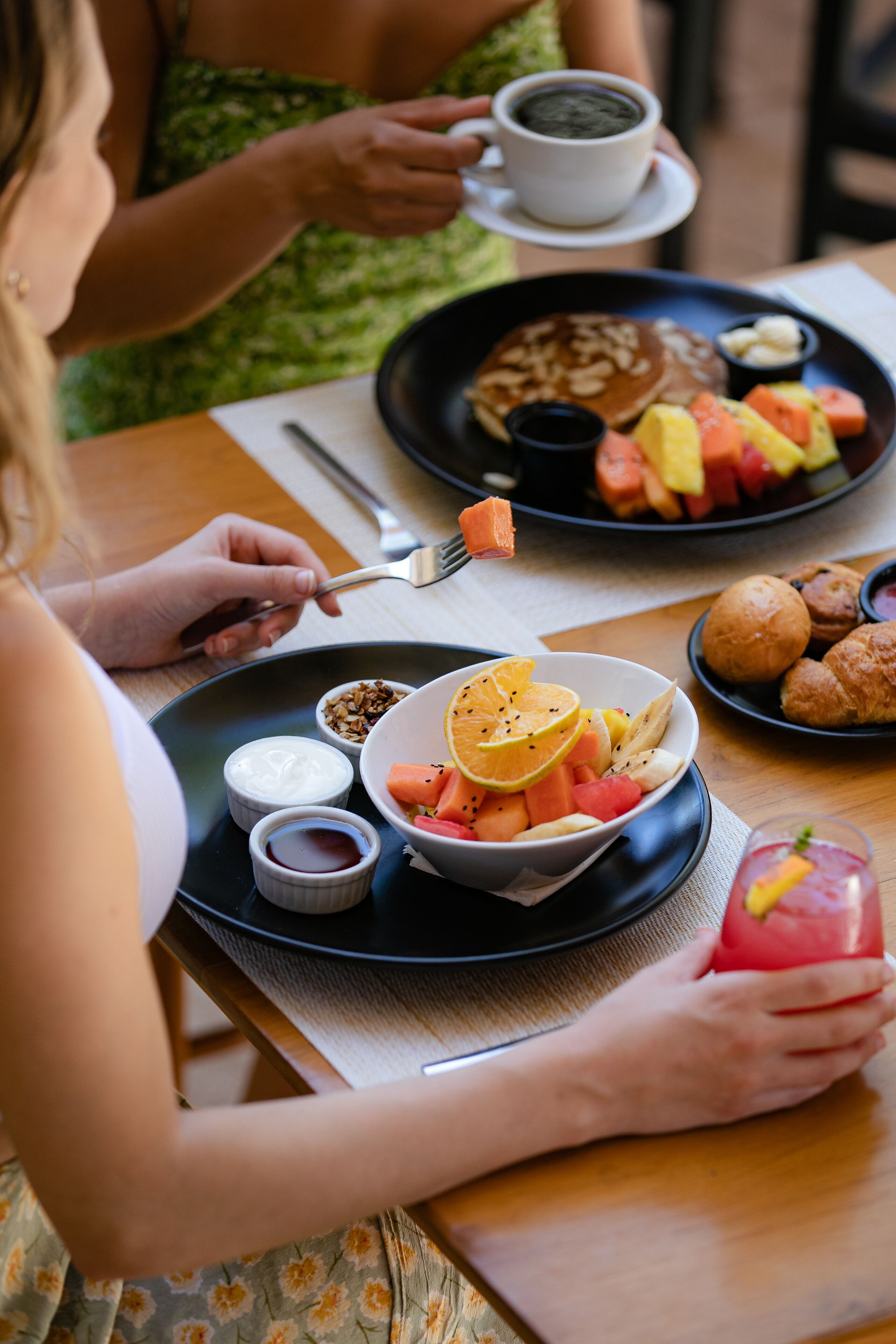 Uma mesa de jantar com pratos de comida, incluindo panquecas, frutas e uma bebida.