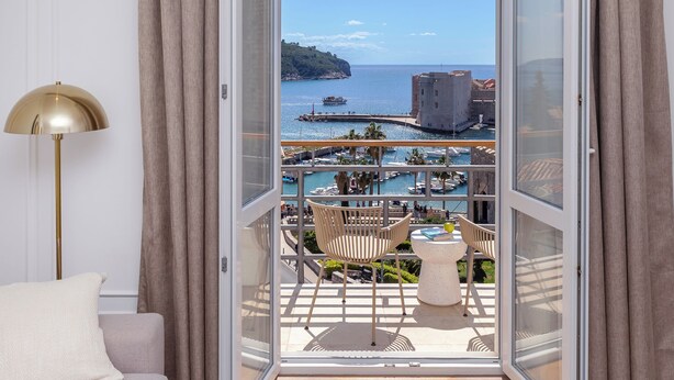 Sala de estar moderna com vista para a costa, incluindo um porto de iates e edifícios históricos.