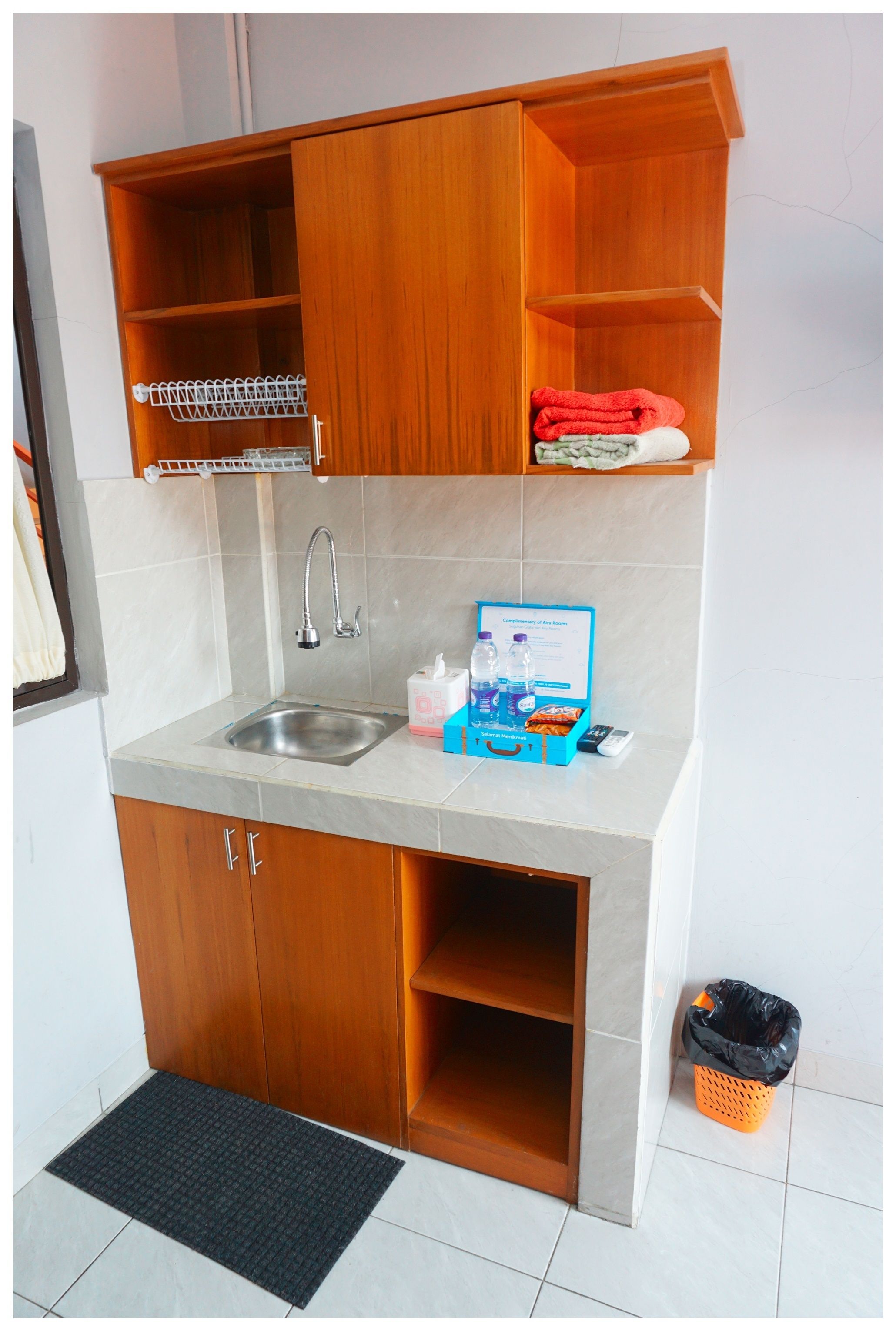 Uma cozinha compacta com armários de madeira, uma pia de aço inoxidável, um balcão pequeno e painel de azulejos.