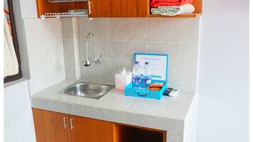Uma cozinha compacta com armários de madeira, uma pia de aço inoxidável, um balcão pequeno e painel de azulejos.