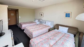 Quarto de hotel com duas camas, uma escrivaninha, uma televisão e uma porta que dá para outro cômodo.