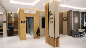 Um lobby moderno de hotel, com balcão de recepção, centro de negócios e área de estar.