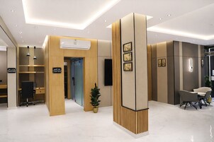 Um lobby moderno de hotel, com balcão de recepção, centro de negócios e área de estar.