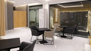 Um interior moderno com parede de vidro, lareira e área de jantar com cadeiras e mesas.