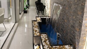 Uma área de recepção moderna com um espelho d'água, assentos e uma parede de tijolos.