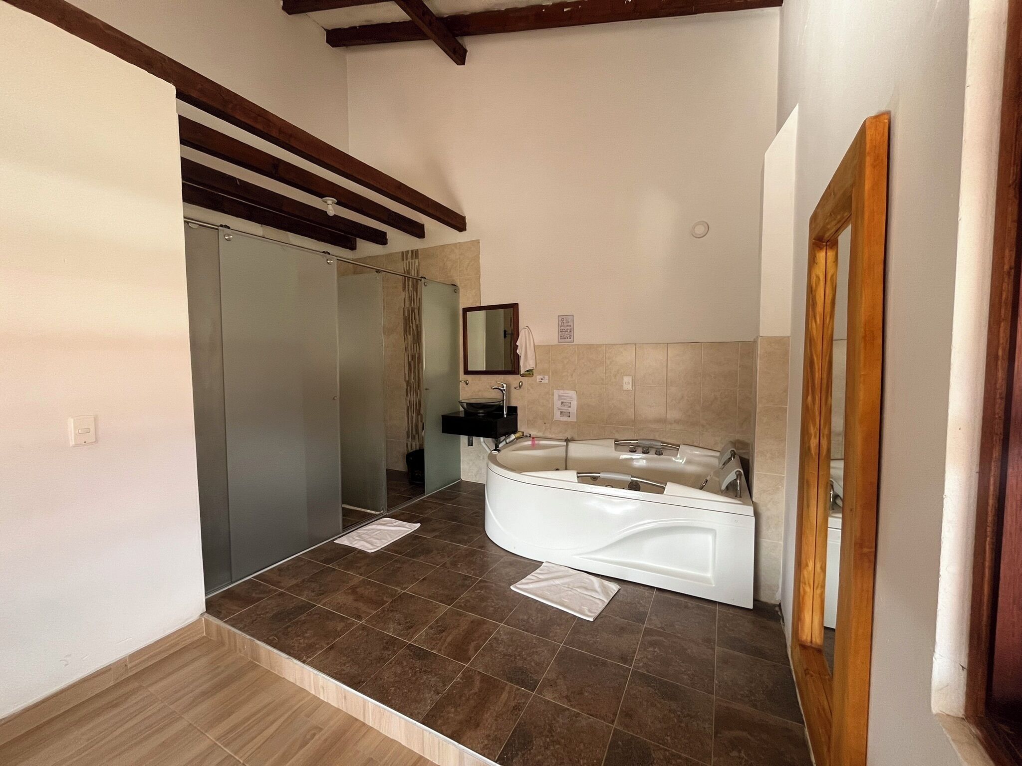 Uma casa de banho moderna com banheira, cabine de duche em vidro e vigamento de madeira no teto.