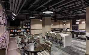 Uma área de estar moderna com diversas opções de assento, mesa de bilhar e bar.