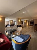 Um hall de hotel espaçoso, com área de refeições, diversas opções de assento e design moderno.