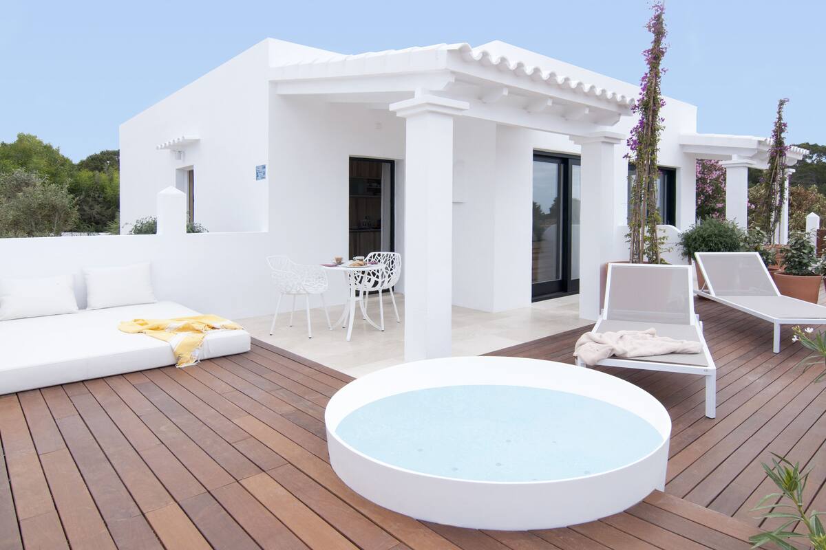 Uma área externa com piscina, um sofá e cadeiras de descanso.