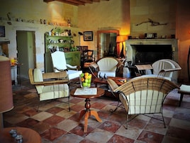 Uma sala de estar aconchegante com móveis de vime, lareira e piso de azulejos.