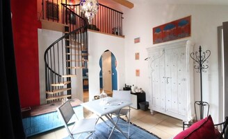 Uma área de refeições com mesa, cadeiras, um lustre, uma escadaria e um armário branco.